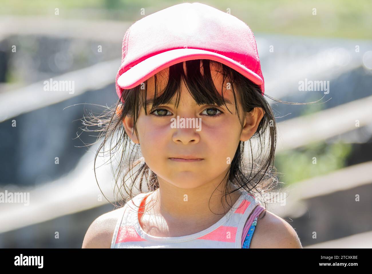 Very close portrait of a latin kid on a trip. The girl wears a pink cap ...
