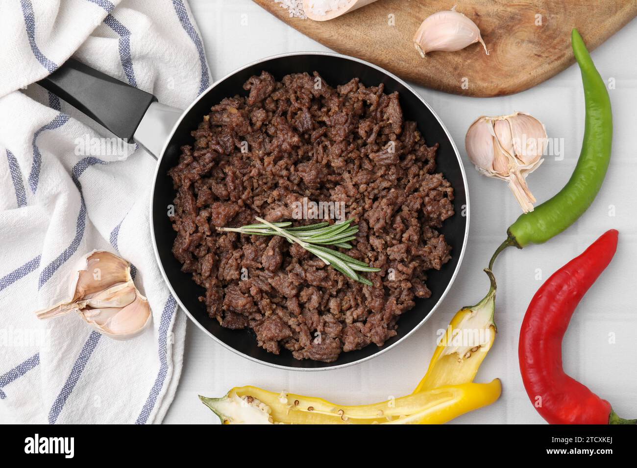 Fried ground meat in frying pan and products on white tiled table, flat ...