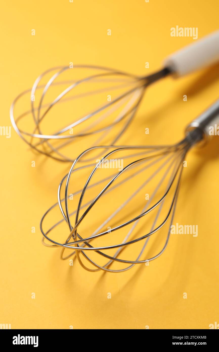 Two metal whisks on yellow background, closeup. Kitchen tool Stock ...