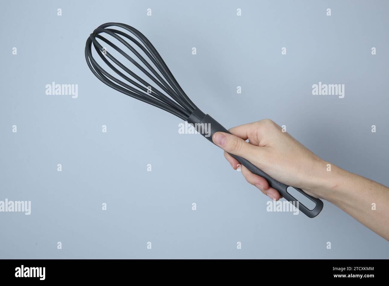 Woman holding plastic whisk on light grey background, closeup Stock ...