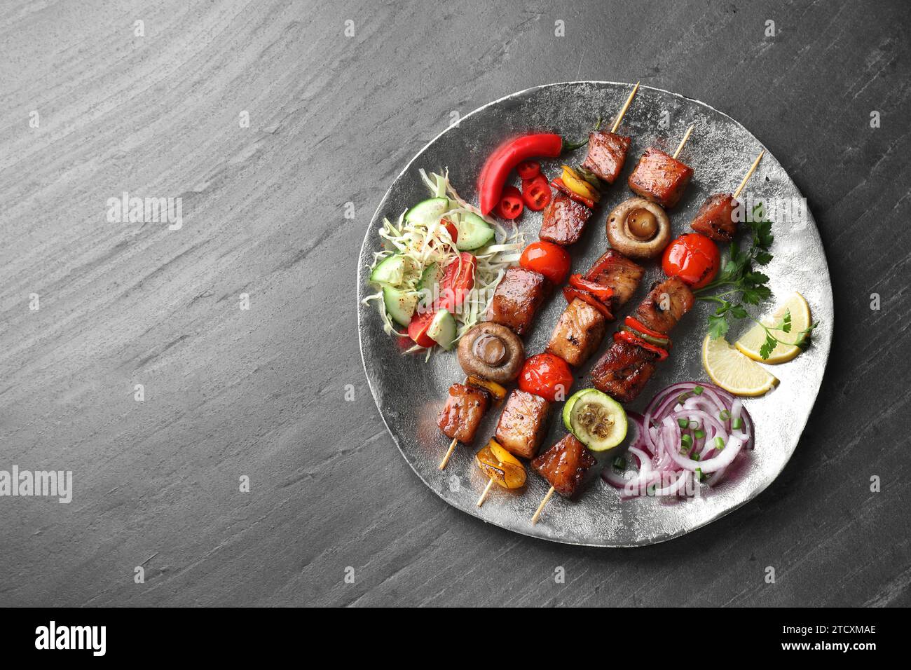 Delicious shish kebabs with vegetables on grey textured table, top view ...