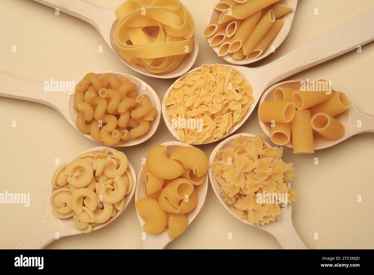 Different types of pasta in spoons on beige background, flat lay Stock ...