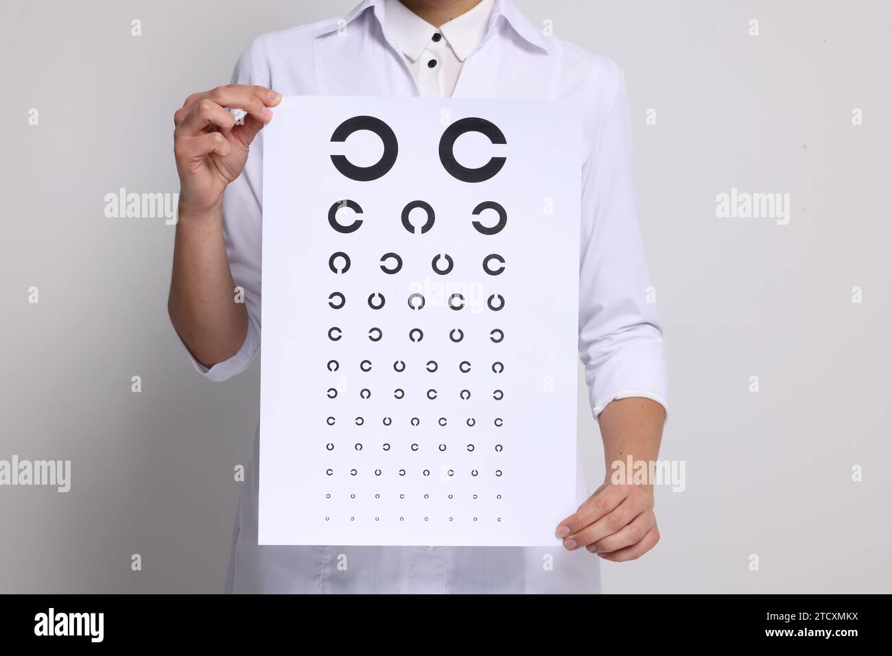 Ophthalmologist with vision test chart on light background, closeup ...
