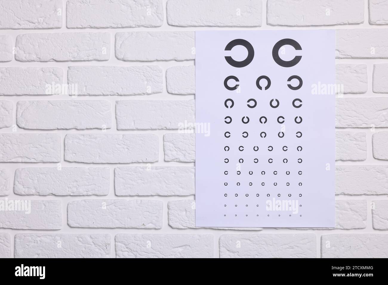 Vision test chart on white brick wall, space for text Stock Photo - Alamy