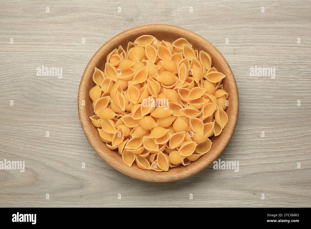 Raw conchiglie pasta in bowl on light grey wooden table, top view Stock ...