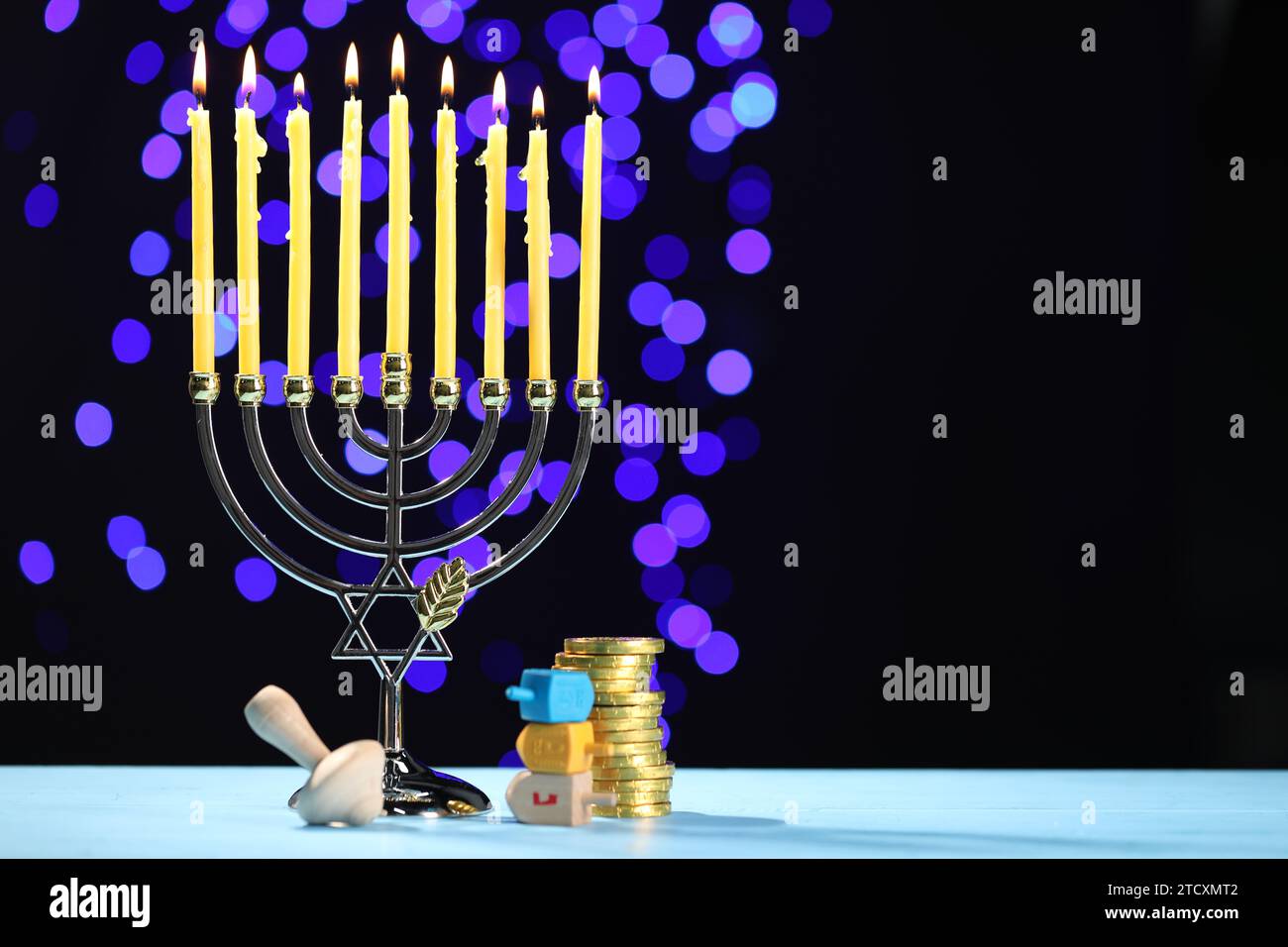 Hanukkah celebration. Menorah with burning candles, dreidels and golden ...