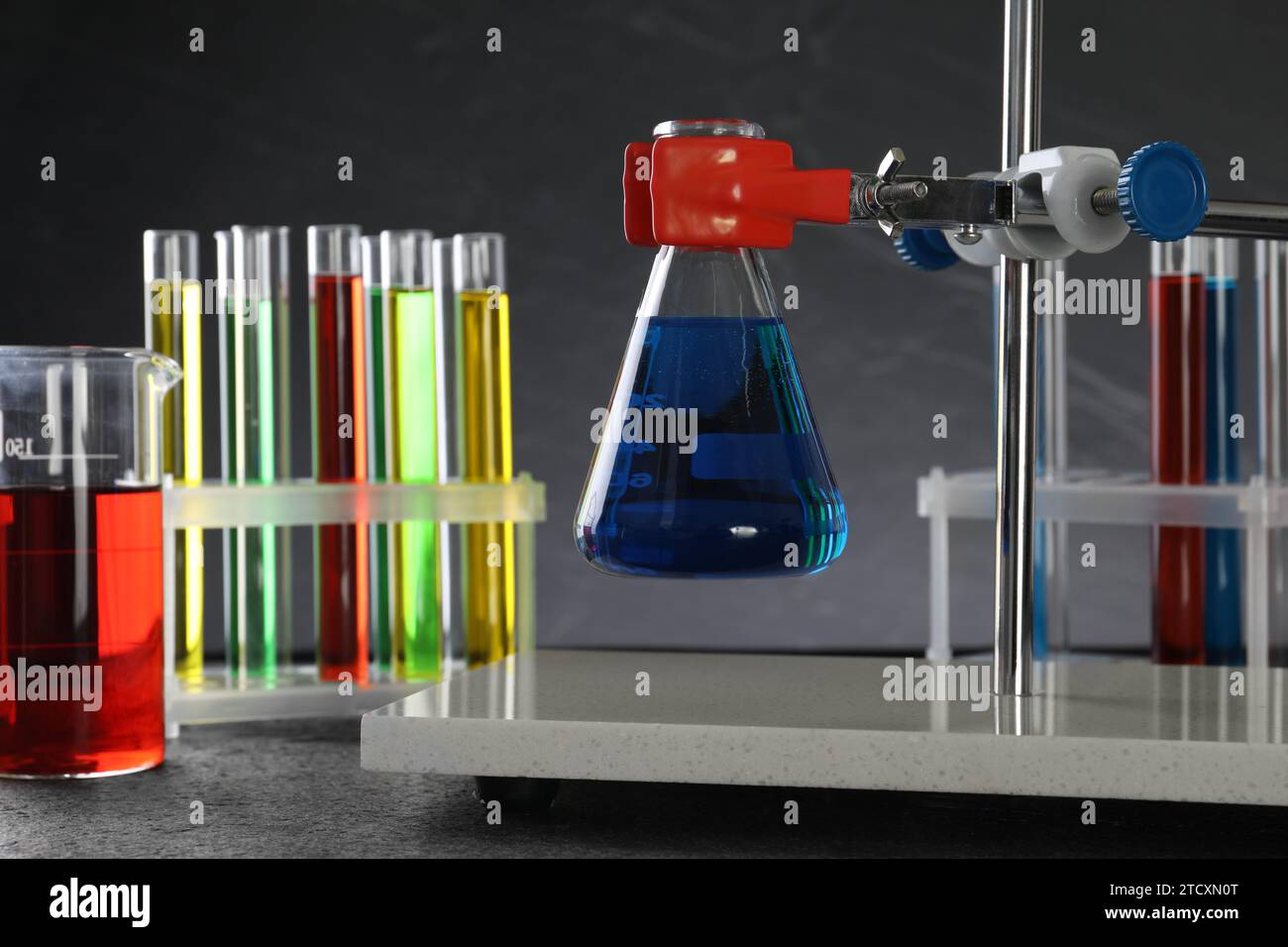 Retort stand and laboratory glassware with liquids on table against ...
