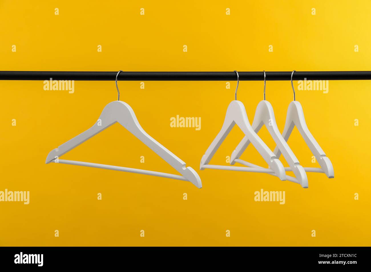 Empty clothes hangers on rack against orange background Stock Photo - Alamy