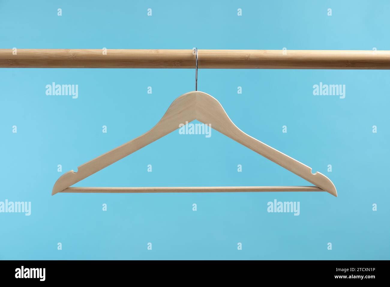 Empty clothes hanger on wooden rack against light blue background Stock ...