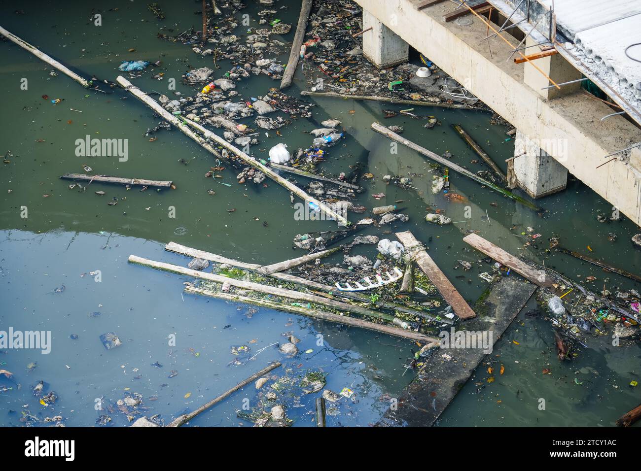 Polluted city canal with large construction debris and small household ...