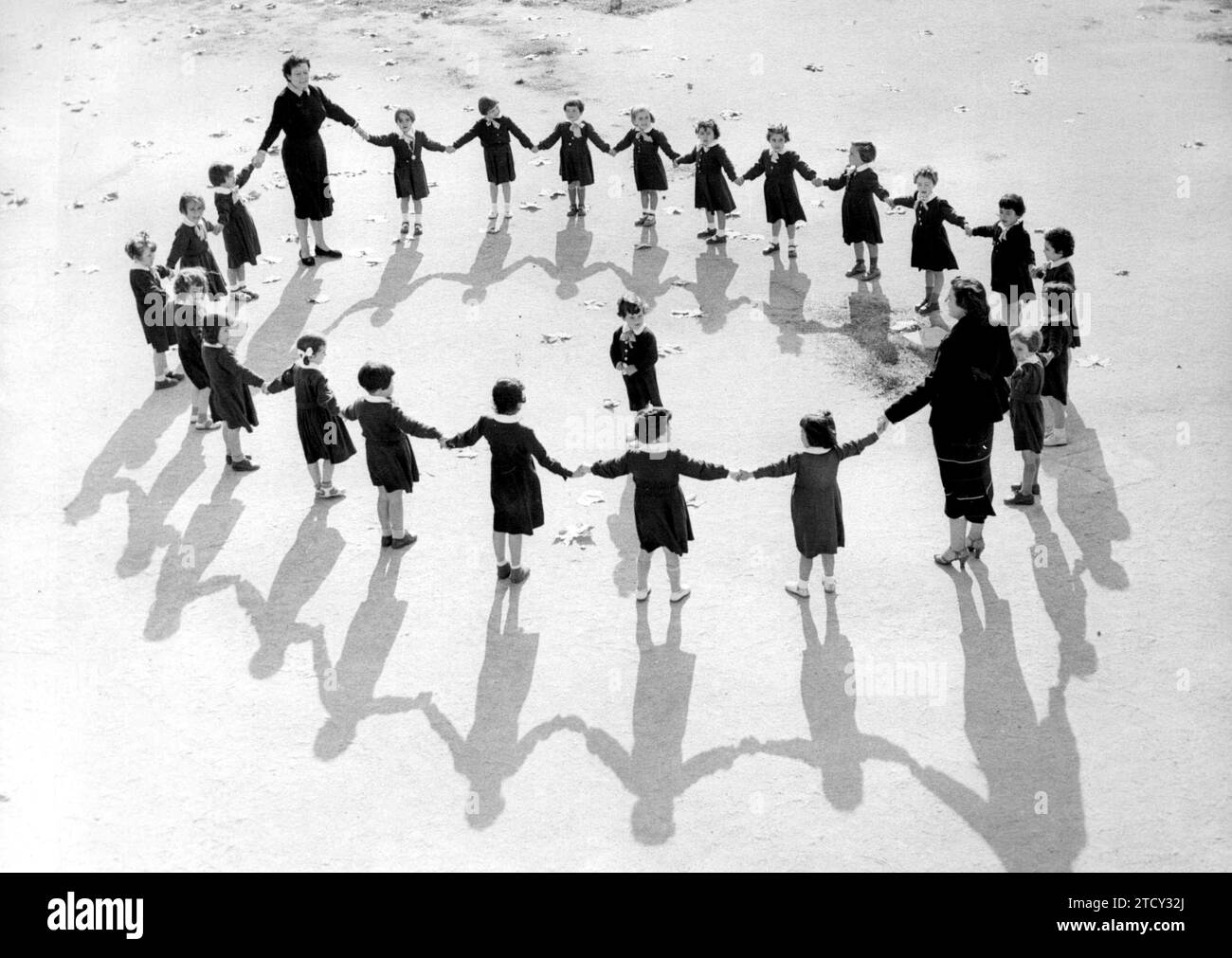 Spain, July 1964. Girls playing in the school yard with the teachers ...