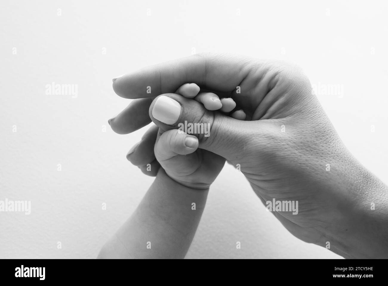 Parents' hands hold the fingers of a newborn baby. Tiny fingers in ...