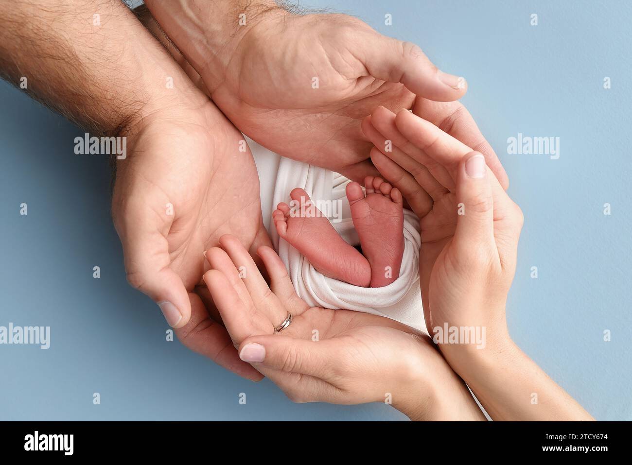 The palms of the parents, father and mother hold the legs, feet of ...