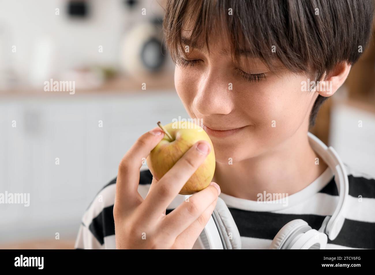 Teenage boy with fresh apple in kitchen Stock Photo - Alamy