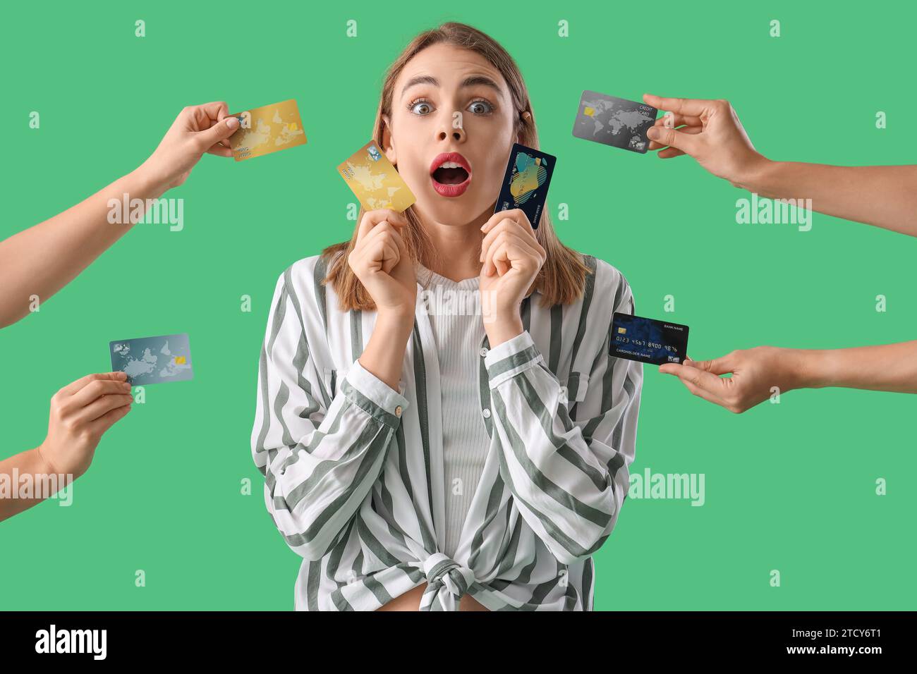 Shocked young woman and hands with credit cards on green background ...