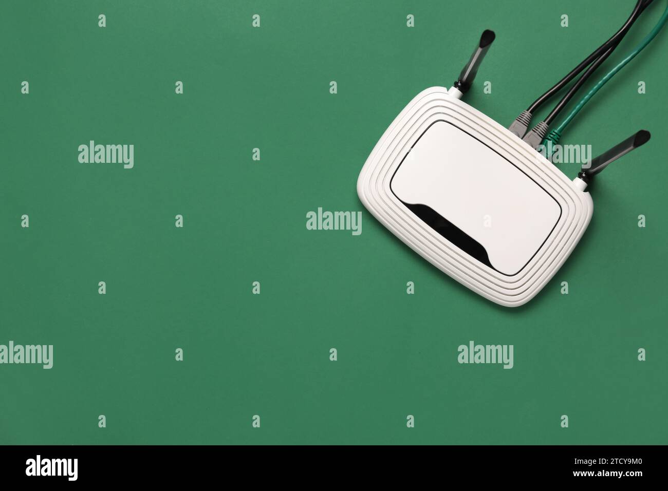 Modern wi-fi router with cables on green background Stock Photo - Alamy