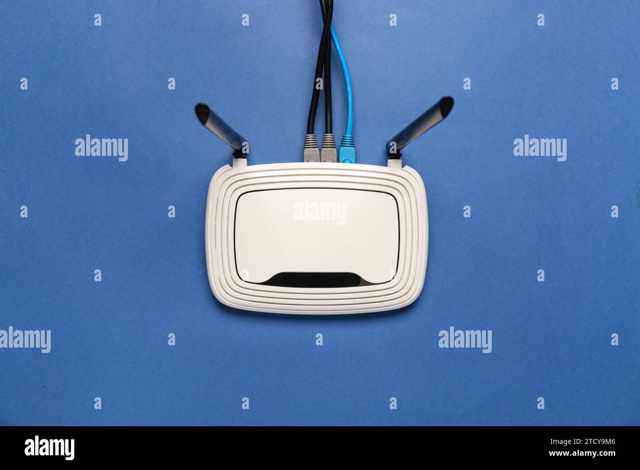 Modern wi-fi router with cables on blue background Stock Photo - Alamy
