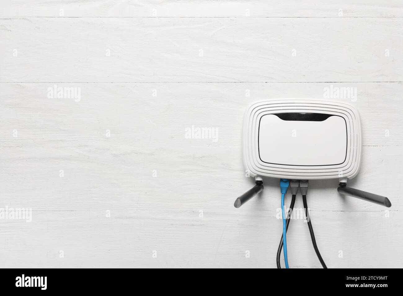 Modern wi-fi router with cables on white wooden background Stock Photo ...