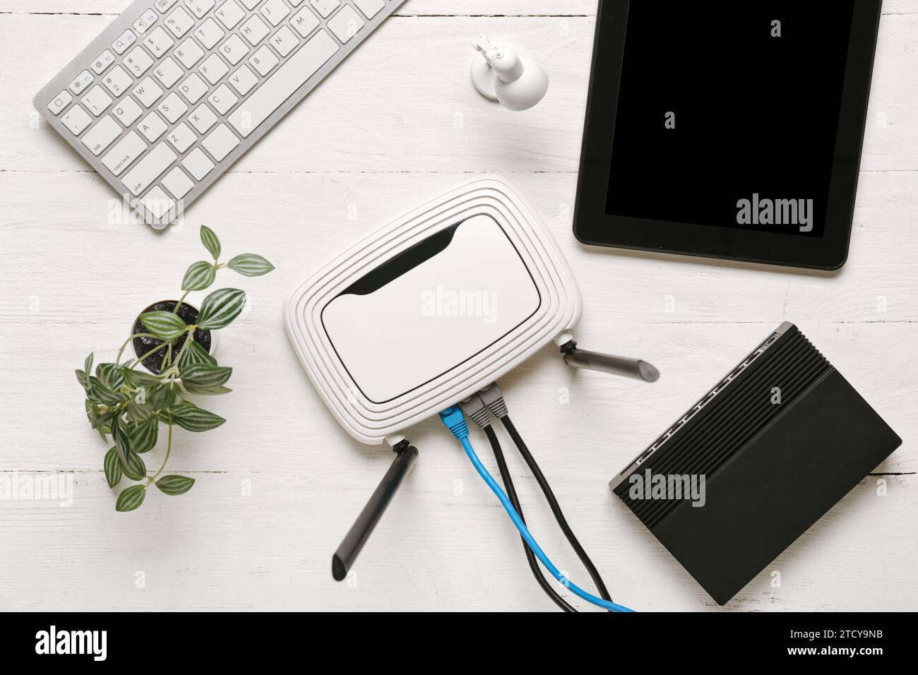 Modern wi-fi router with keyboard and tablet computer on white wooden ...