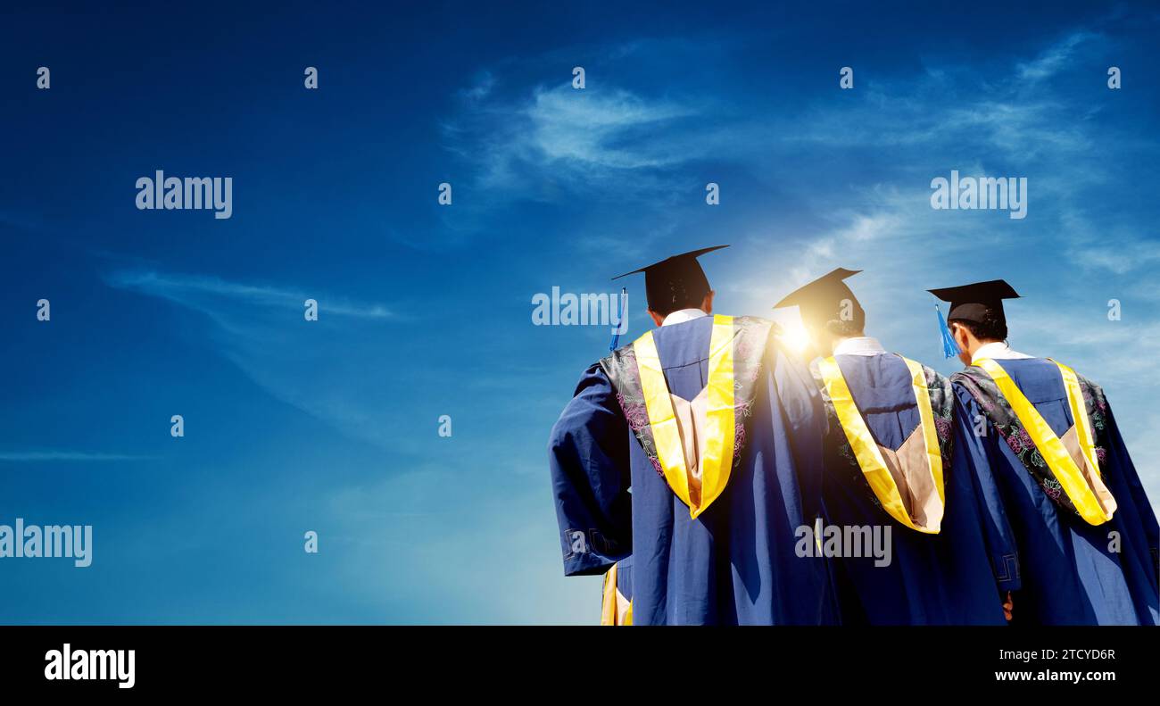 Rear view of three graduates standing in a line against blue sky Stock ...