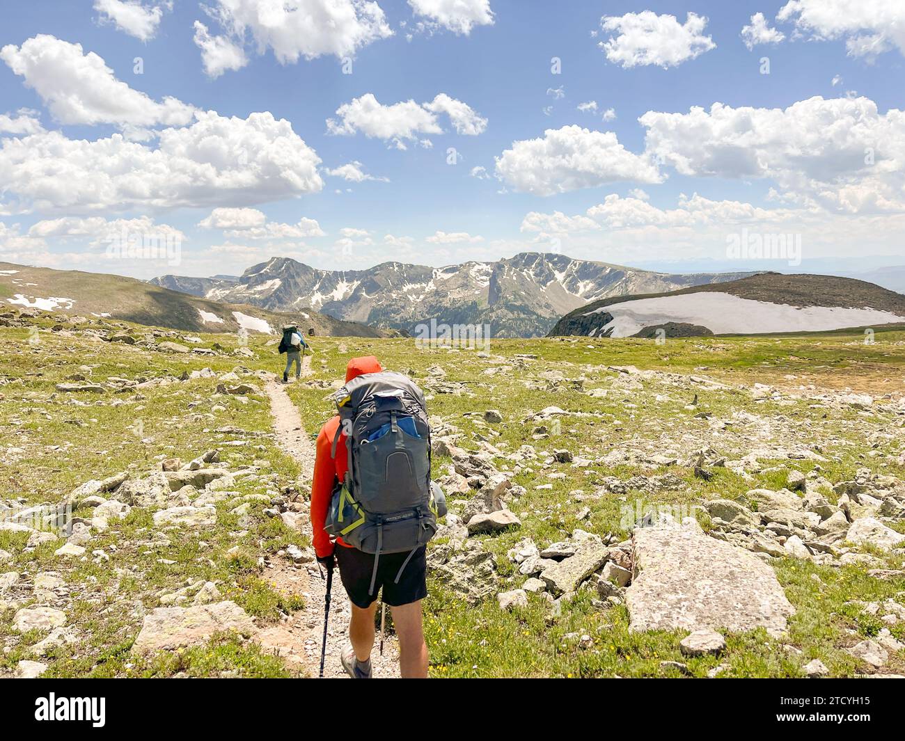 Two hikers follow a trail in Rocky Mountain National Park, their ...