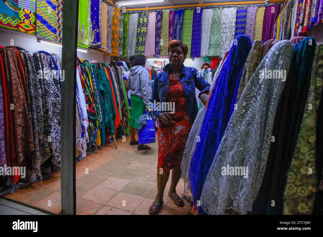 A consumer is checking on fabric products at a textile shop in Biashara ...