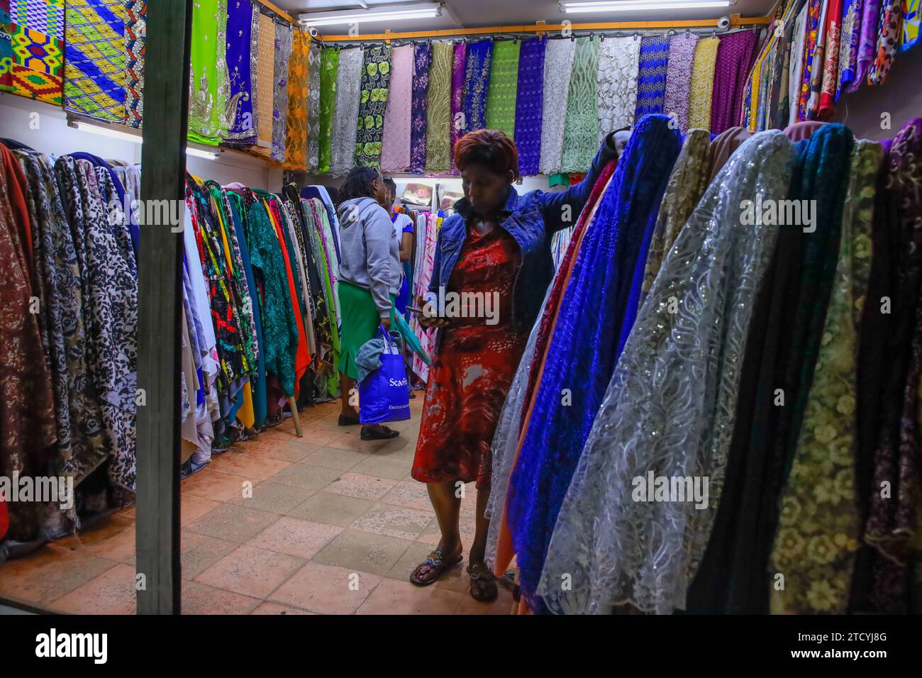 A consumer is checking on fabric products at a textile shop in Biashara ...