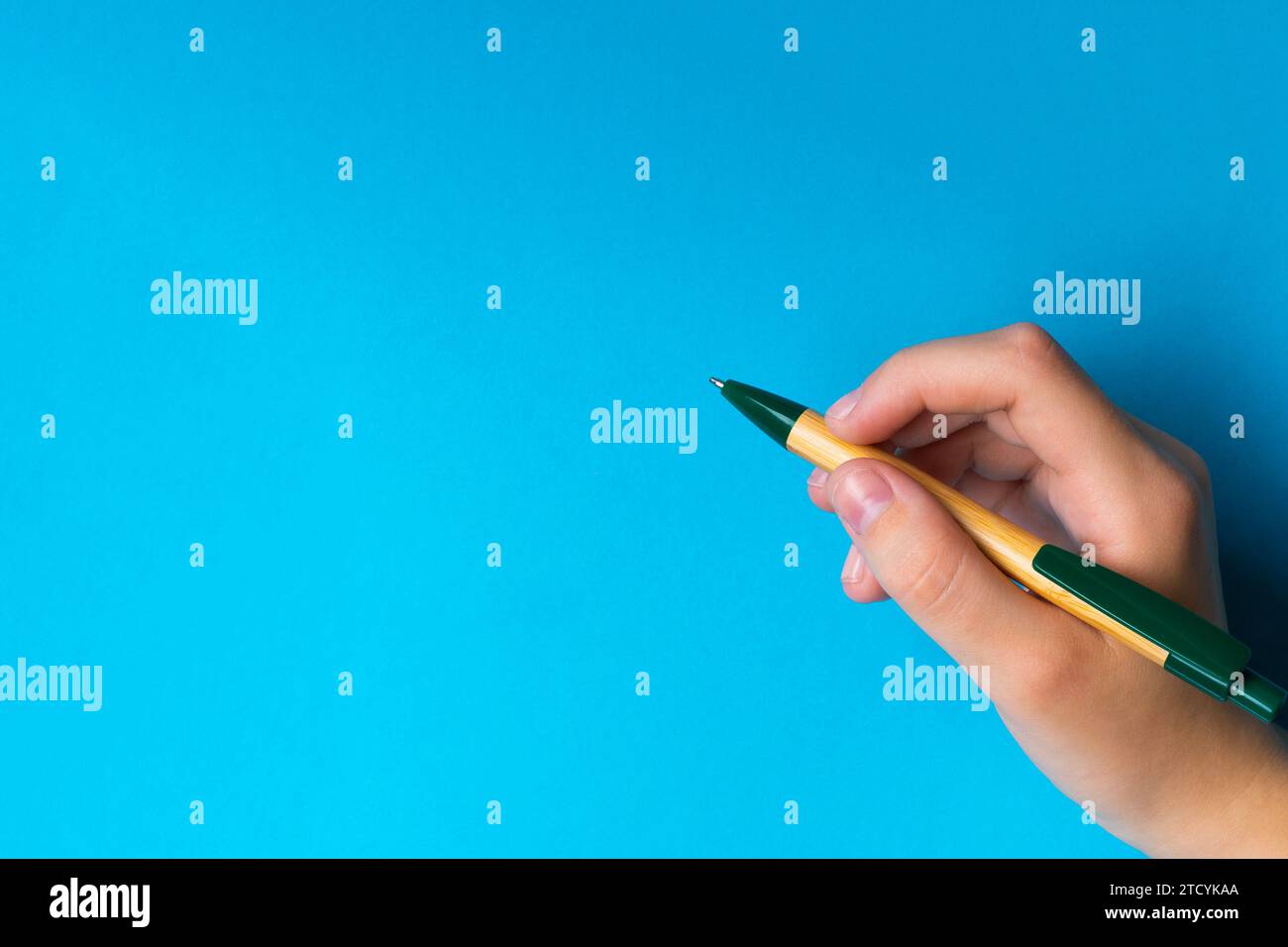 Children hand with pen write on an blue white background. Writing hand ...