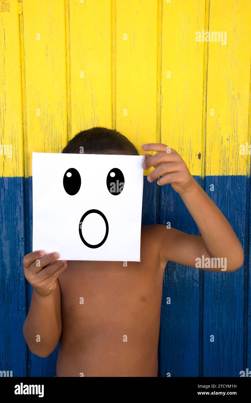Boy with surprise emoticon on a coloured wooden background Stock Photo ...
