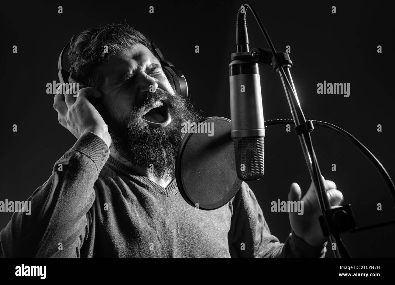 Singing man in a recording studio. Expressive bearded man with ...