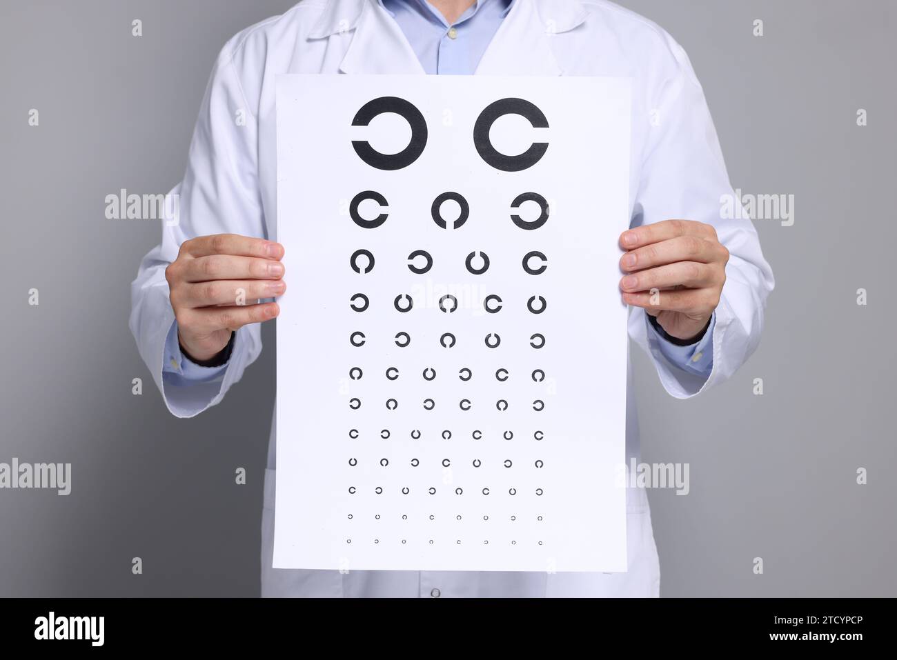 Ophthalmologist with vision test chart on gray background, closeup ...