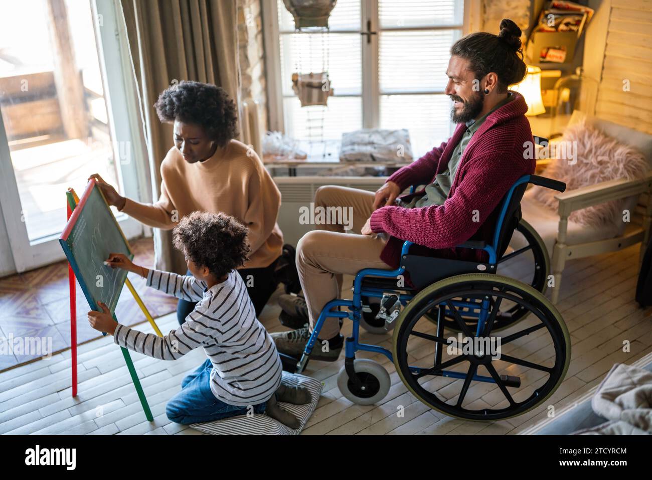 Happy multiethnic family with disability. Father in wheelchair enjoying ...