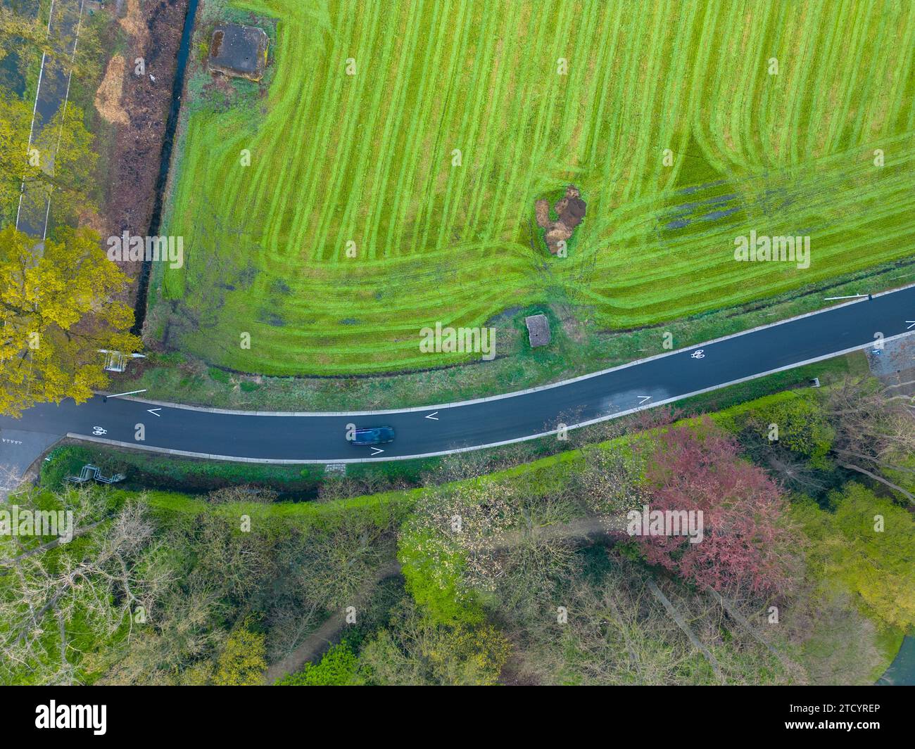 This aerial photograph captures a sweeping view of a curving asphalt ...