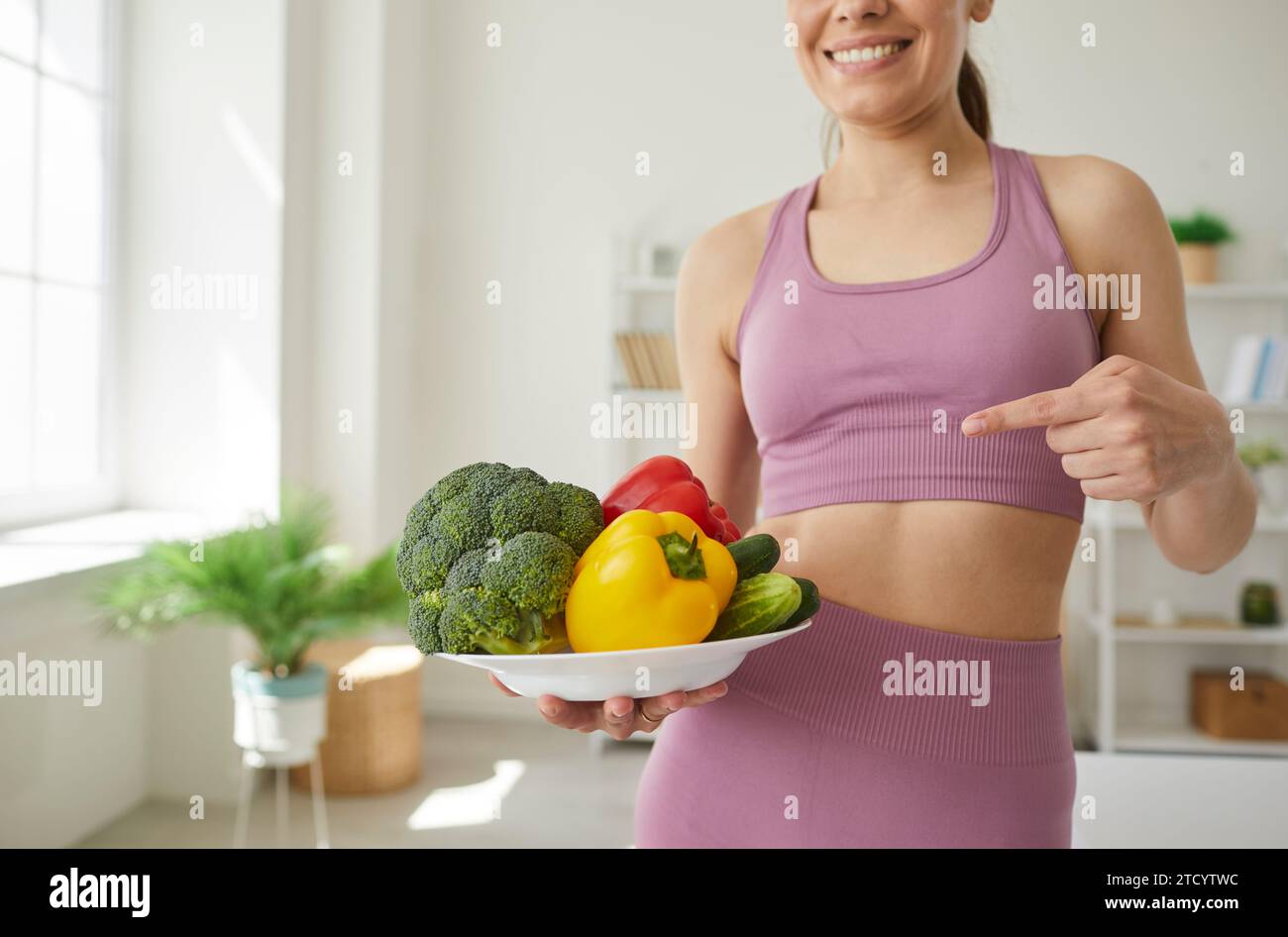 Happy young slim woman keeps fit and healthy by exercising and eating ...