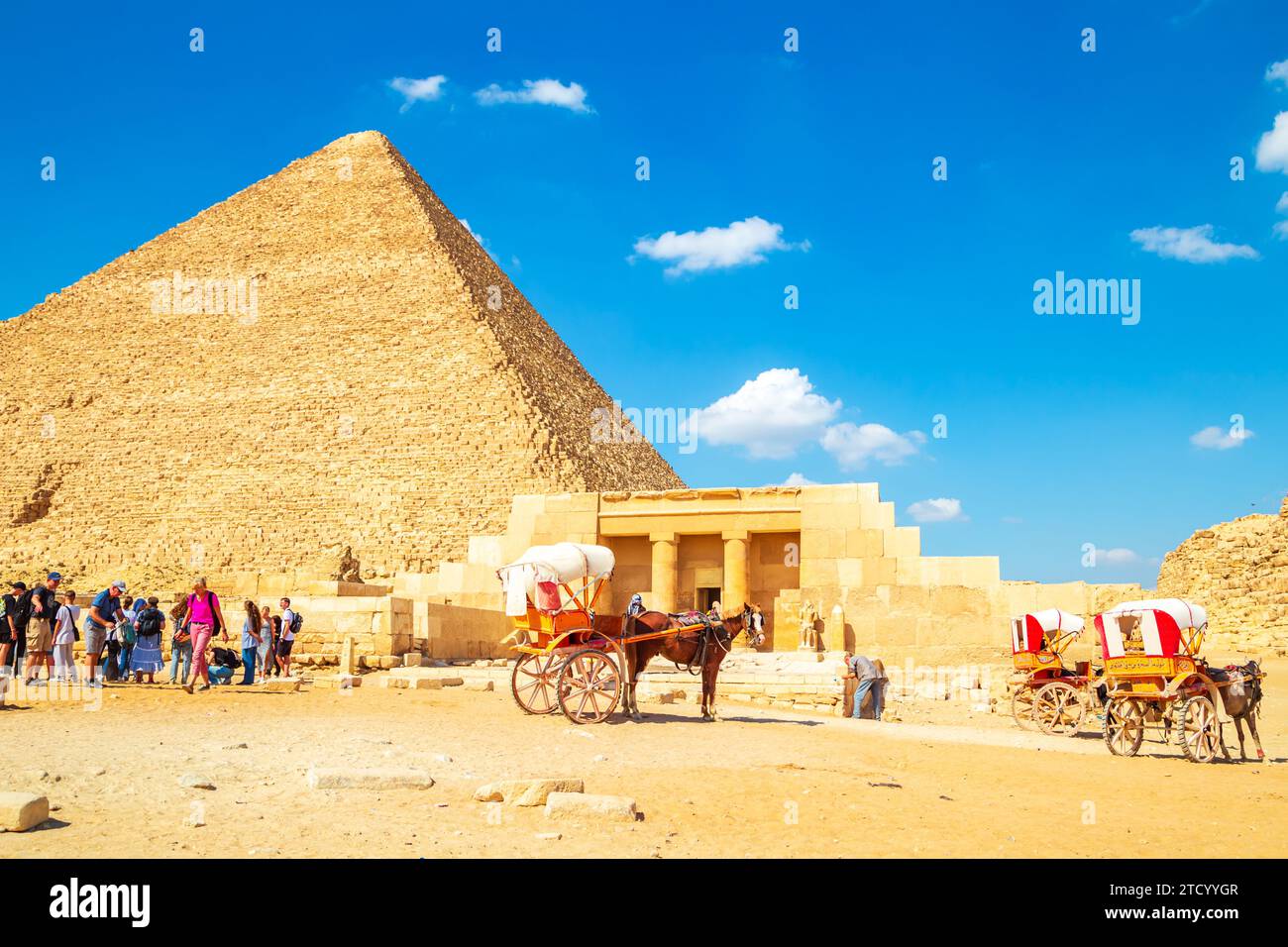 Horse-drawn carriages carry tourists near the Great Pyramids of Egypt ...