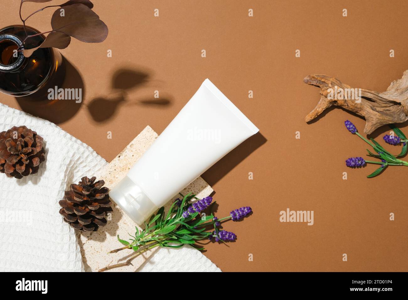 An unlabeled cosmetic tube, fresh lavender flowers, a brown glass vase ...