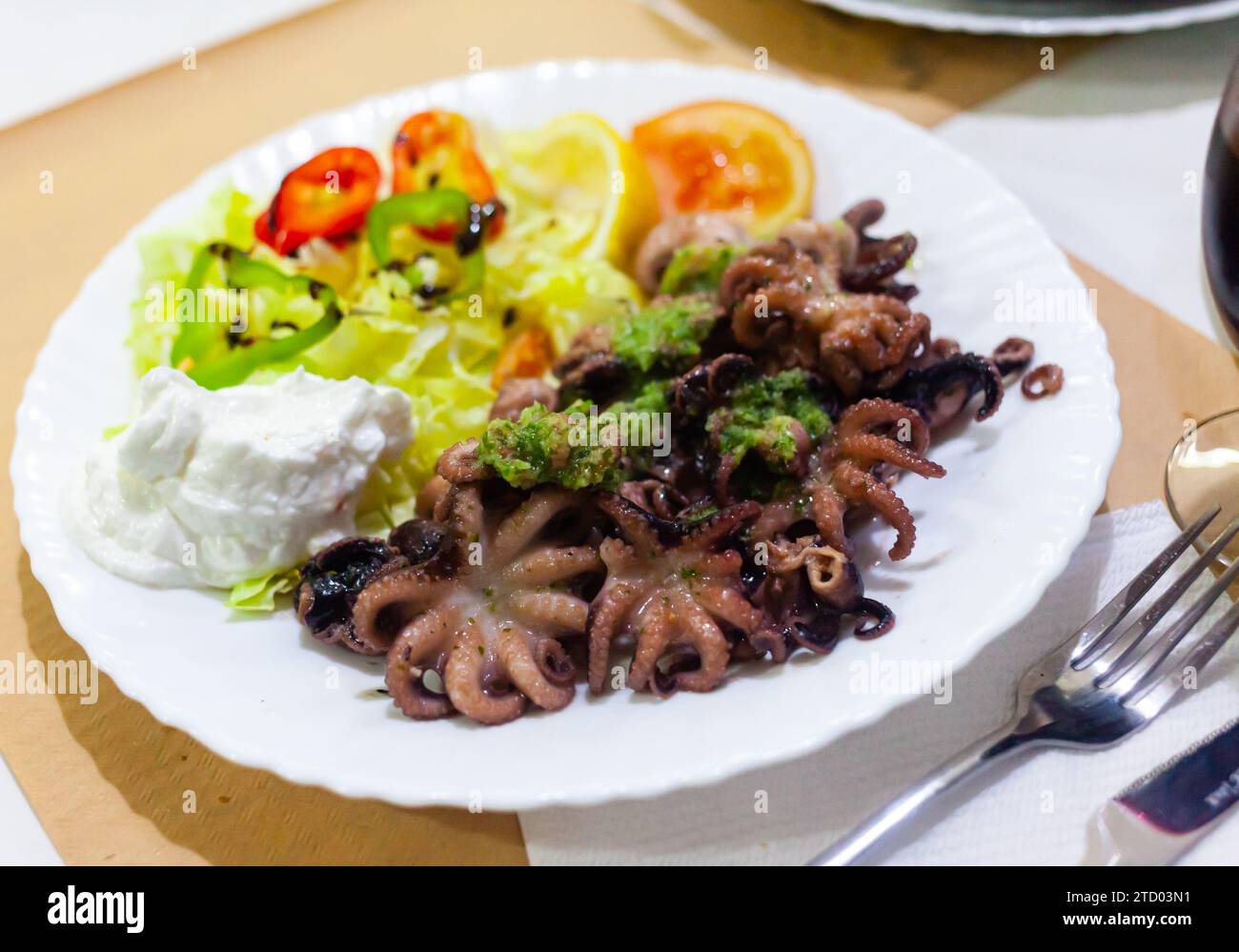 Small fried octopus with sour cream and vegetables Stock Photo - Alamy