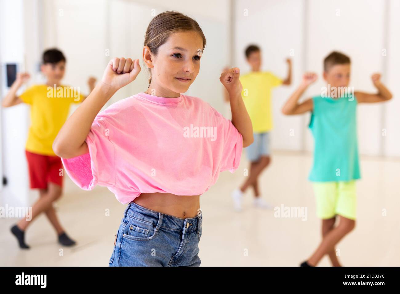 Cheerful preteen girl learning energetic dance in choreography class ...