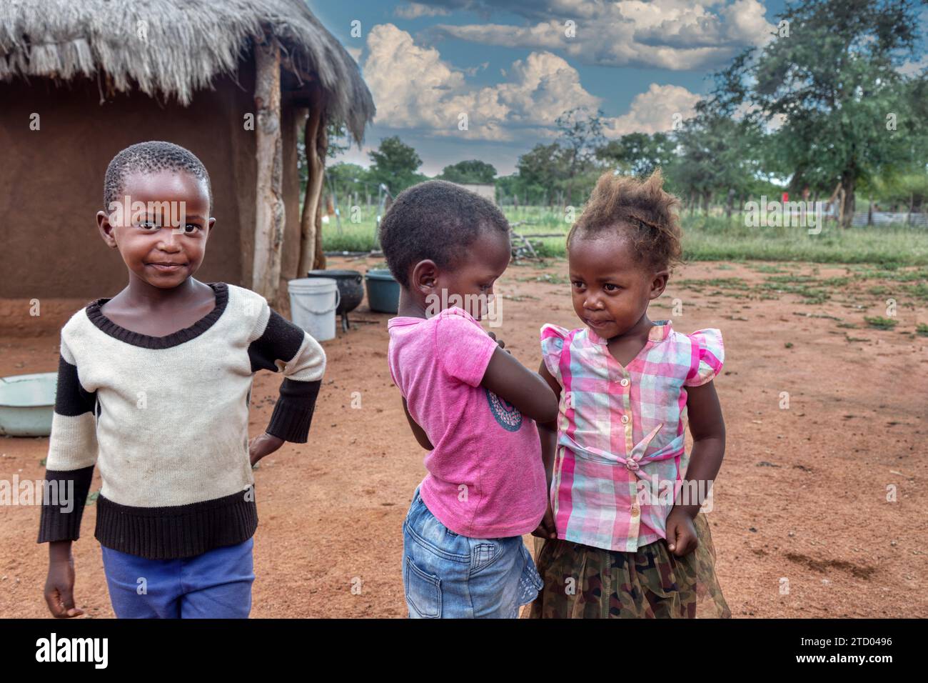 village african kids, playing in the yard , three siblings, hut with ...