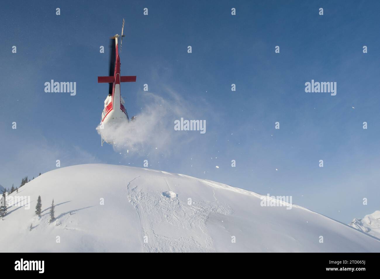 A helicopter flies over a bomb crater from avalanche control work Stock ...