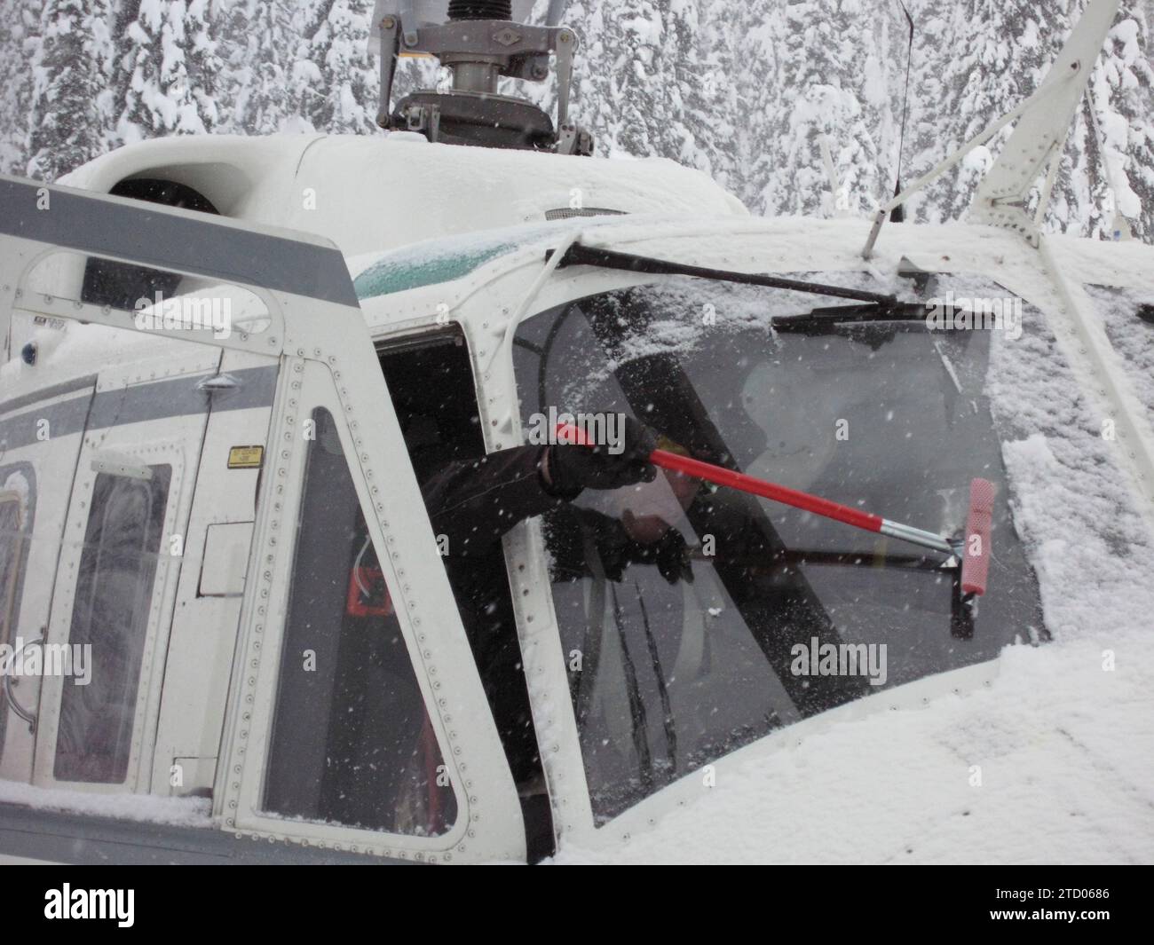 A heli-ski pilot cleans snow from his window Stock Photo - Alamy
