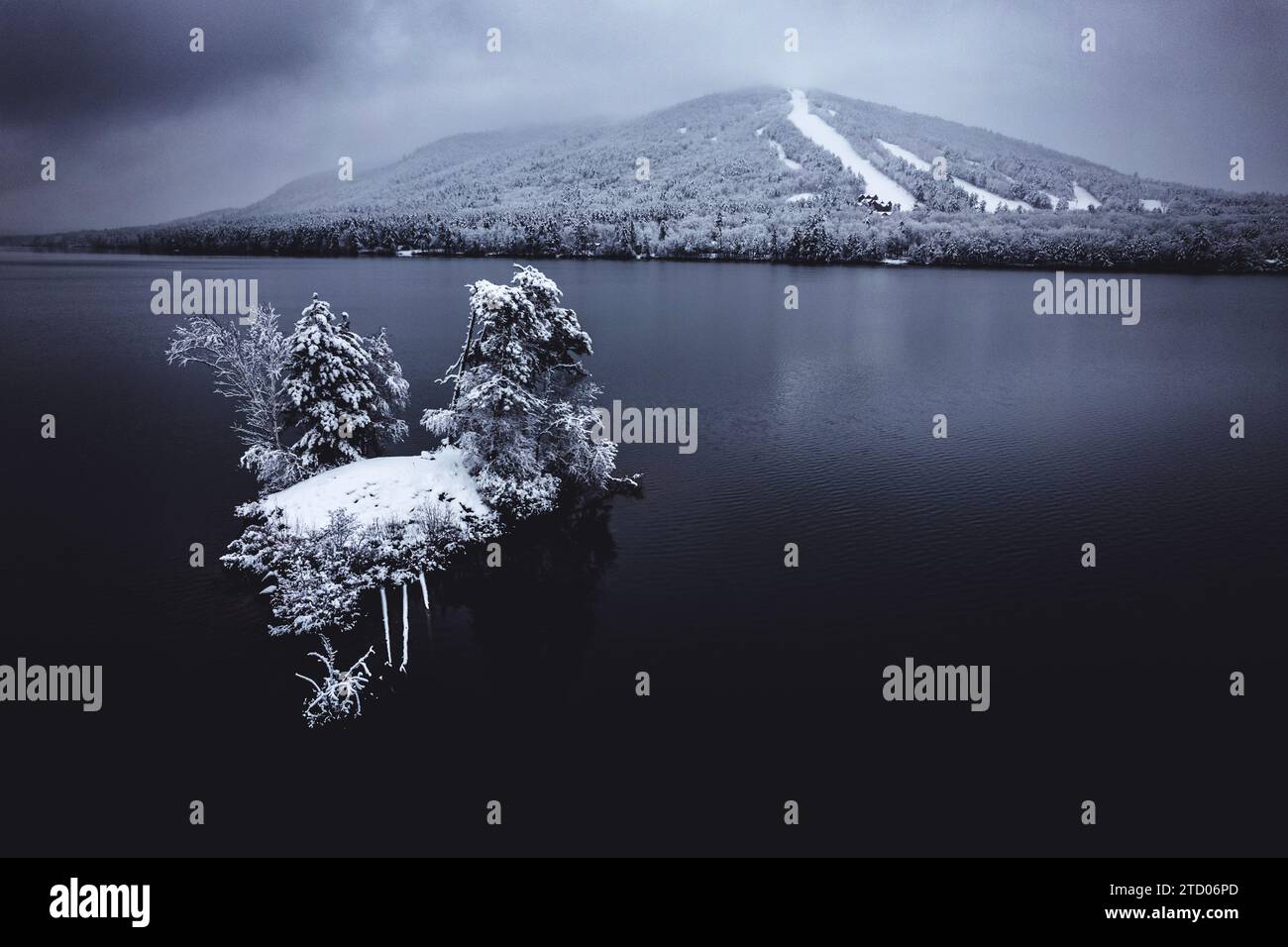 Snow covered island in a lake with ski mountain in the background Stock ...