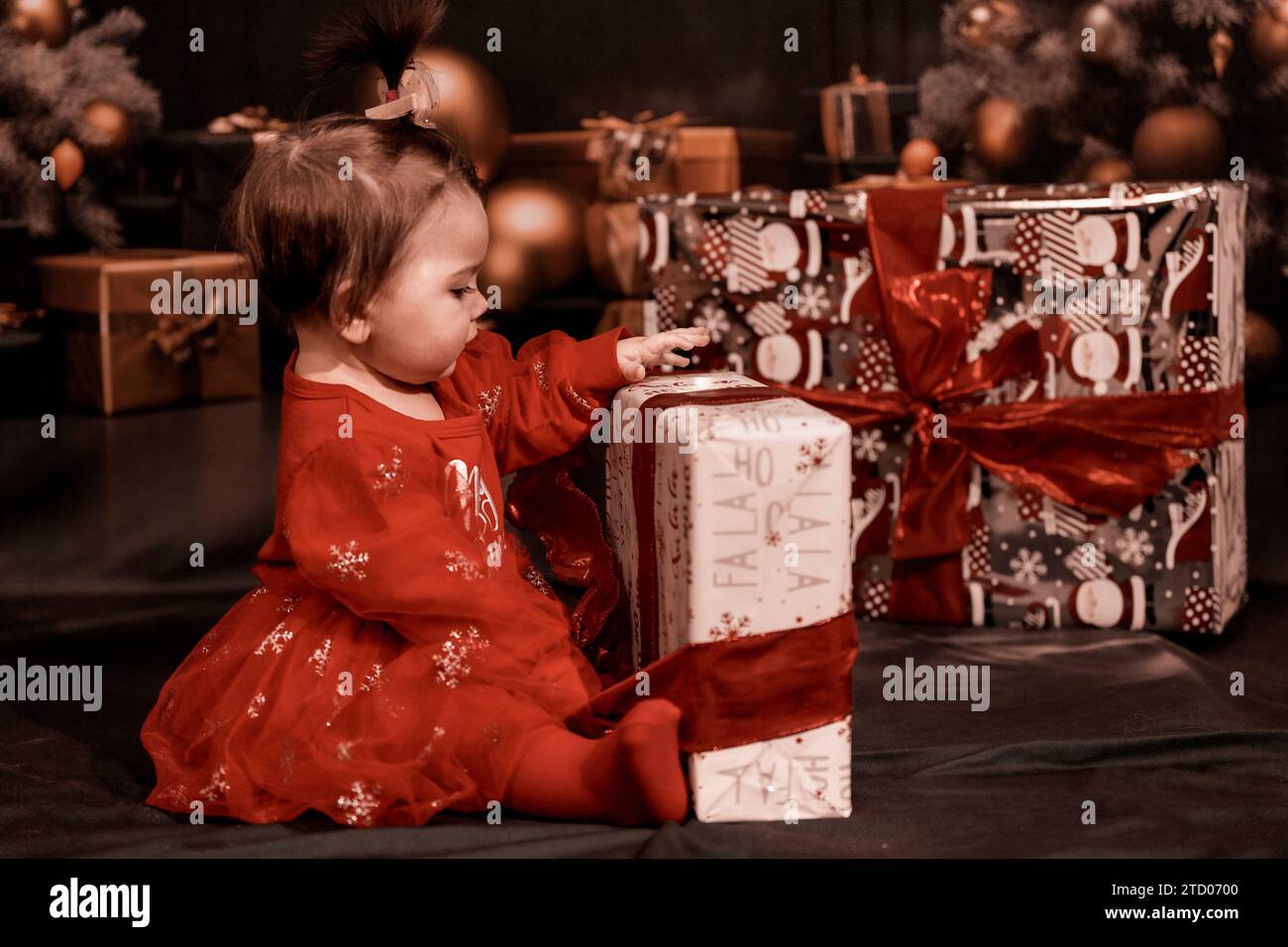 A baby girl in front of a present the same size as her Stock Photo - Alamy