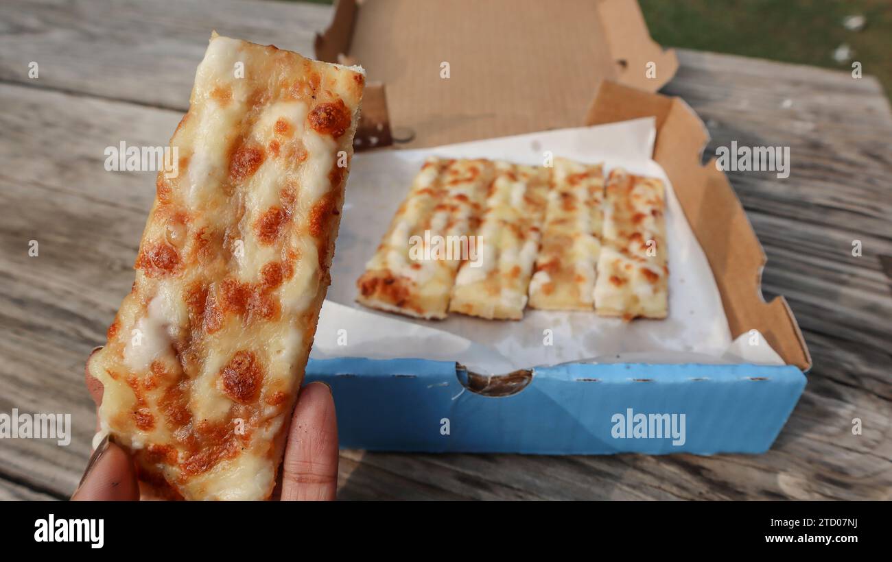 Female holding eating Cheesy garlic Pizza Bread sticks. Baked cheese ...