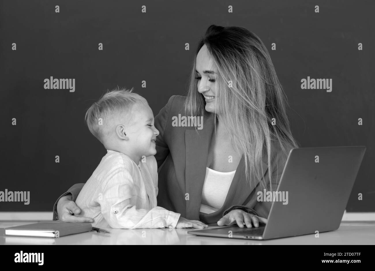 Mother and son together using computer laptop. Elementary school classroom. Teacher and ...