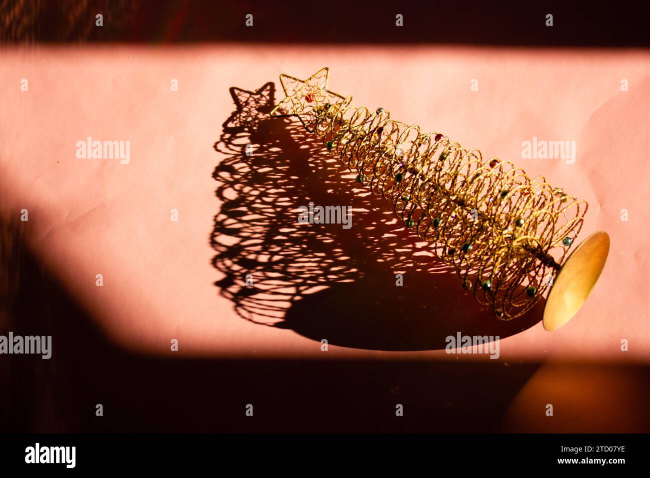 Decorative Christmas tree with a golden star on a top on pink table ...