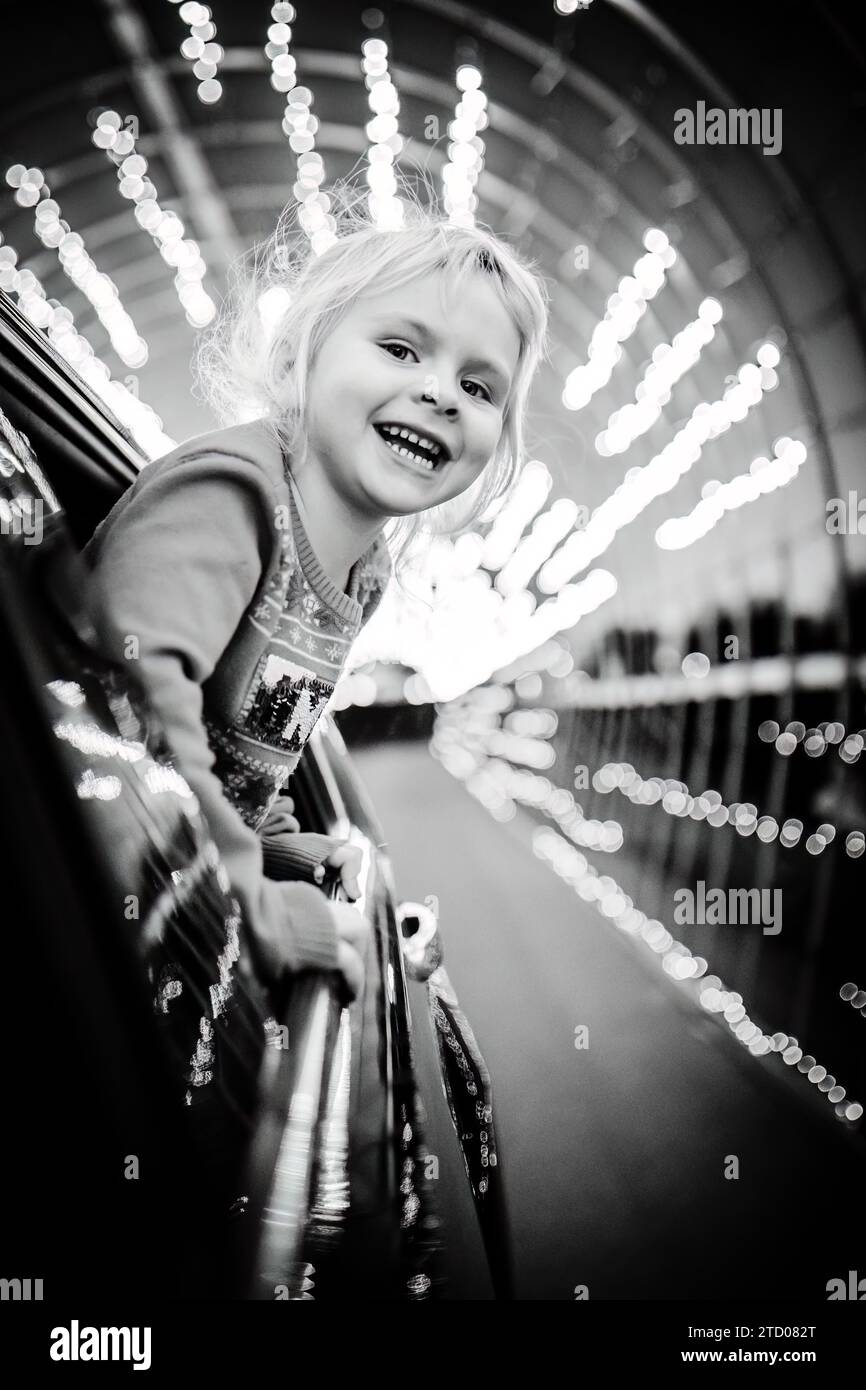 Happy kid looking at festive holiday lights from car window Stock Photo ...