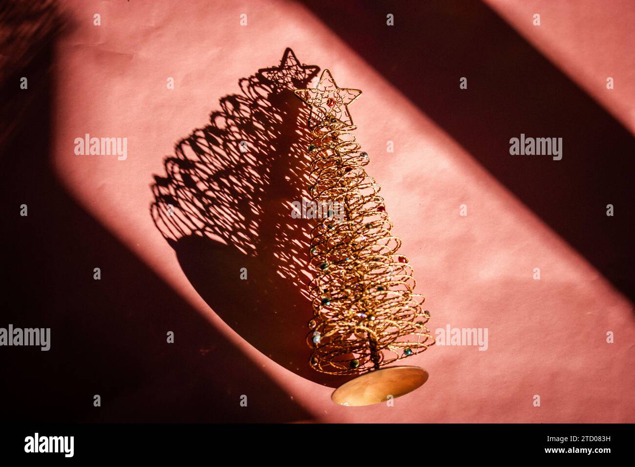 Decorative Christmas tree with a golden star on a top on pink table ...