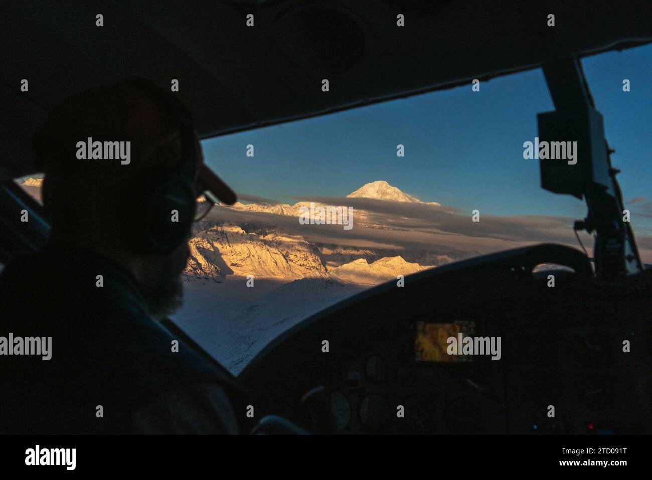 Male pilot navigates the Alaska range with Denali at sunset Stock Photo ...