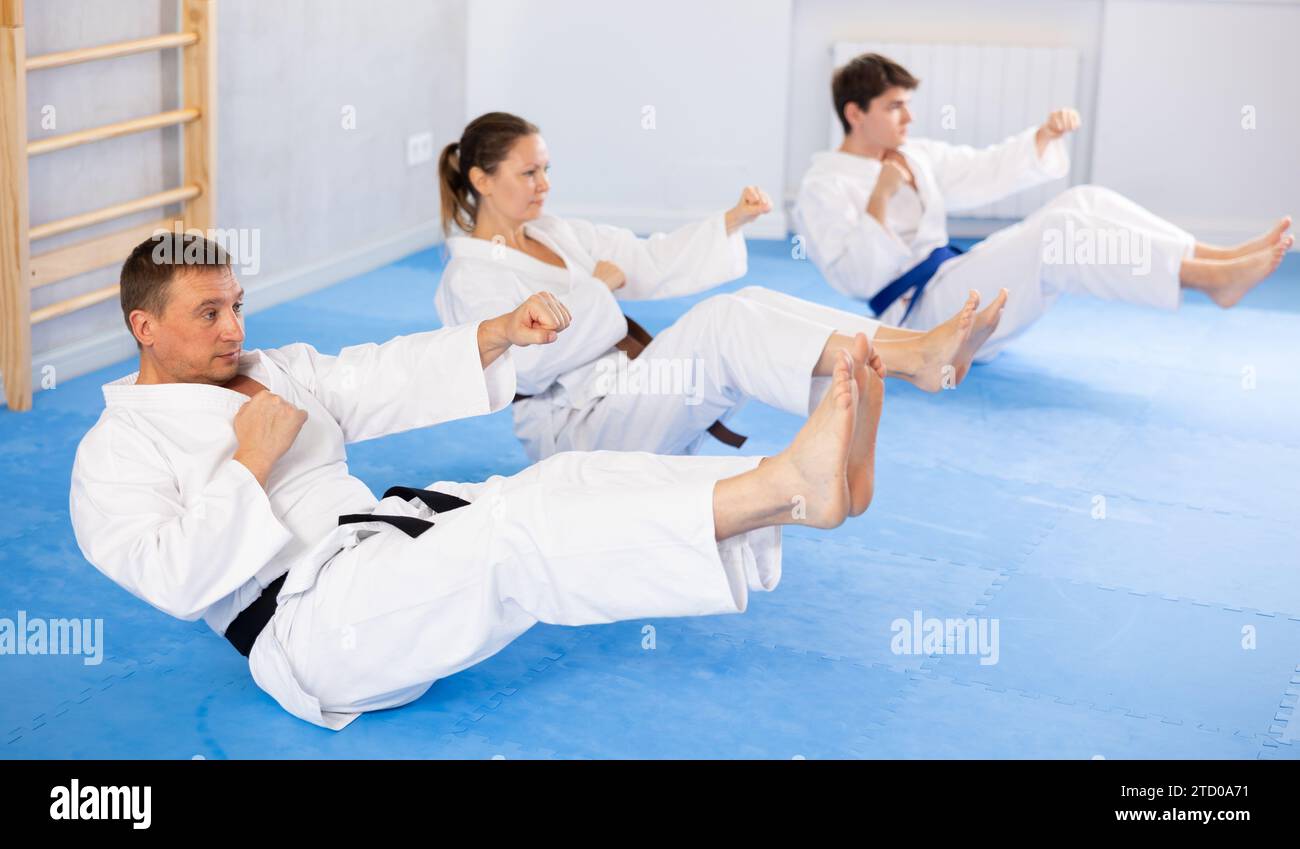 Woman and men in kimono train abdominal muscles and do punches at same ...